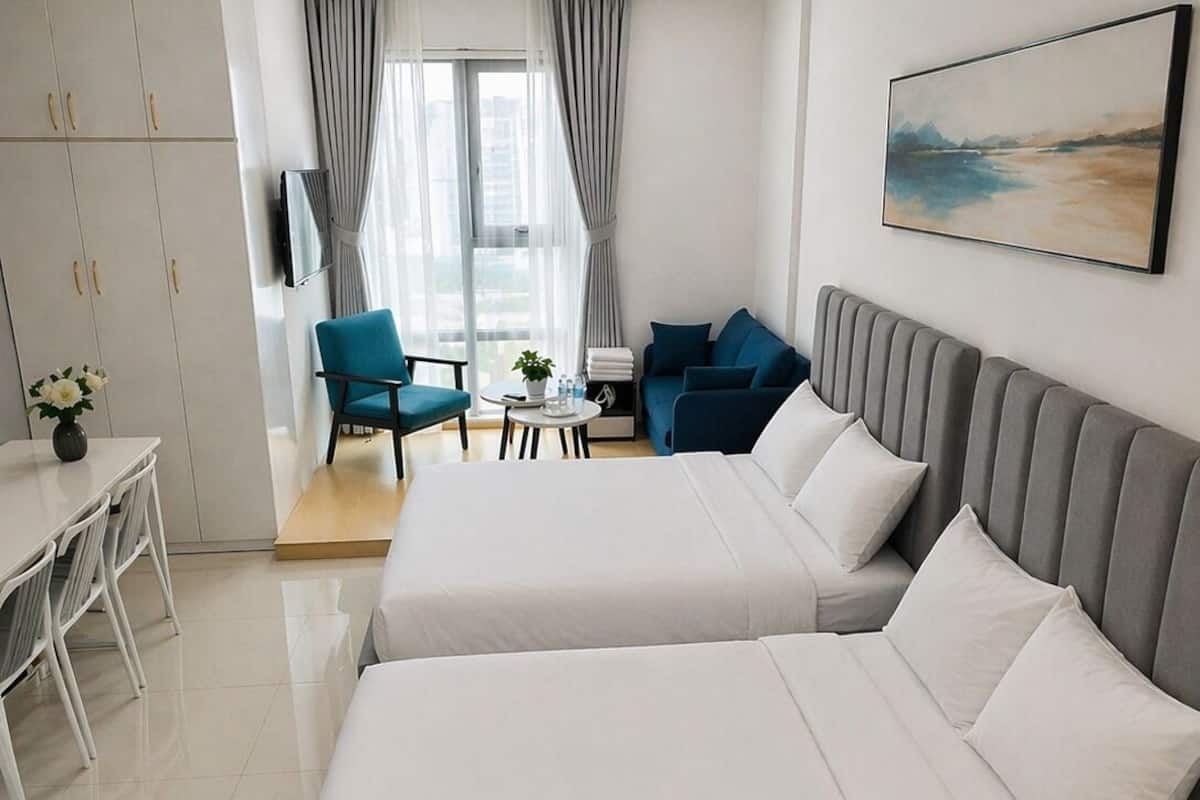 Quarto de hotel com duas camas, uma escrivaninha, uma cadeira, uma televisão e um quadro na parede.