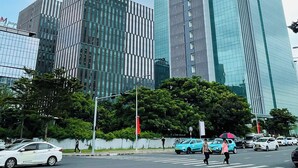 Paisagem urbana com edifícios modernos altos, uma faixa de pedestres e pessoas.