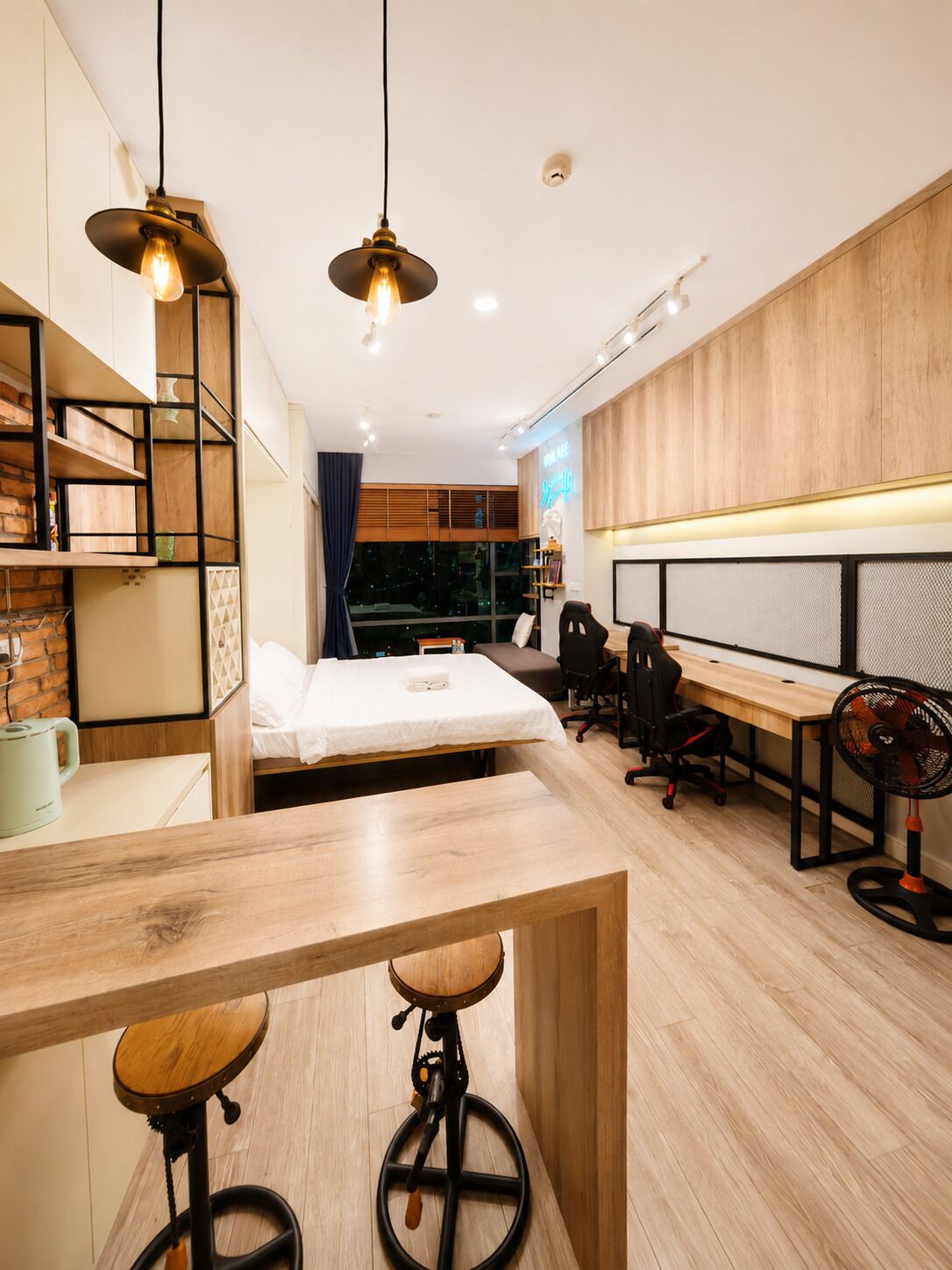 Quarto de hotel moderno com cama, secretária e área de estar.