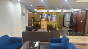 Um hall com sofás azuis, uma mesa de centro de vidro, um balcão de recepção e um letreiro com a inscrição 'Welcome to Transquil'.