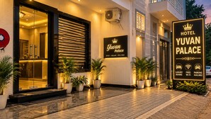 Entrada de um hotel com placa indicando 'Yuwan Palace' e comodidades como quartos de luxo, Wi-Fi gratuito e estacionamento.