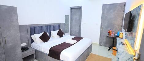 Quarto de hotel moderno com cama, guarda-roupa, escrivaninha e televisão.