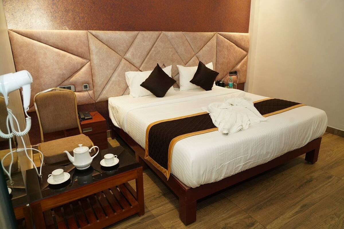 Quarto de hotel com uma cama grande, uma mesa de cabeceira com telefone e uma chávena, e uma cadeira.