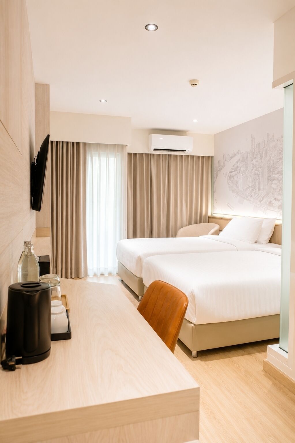 Quarto de hotel com cama, escrivaninha com cadeira, televisão e ar condicionado.