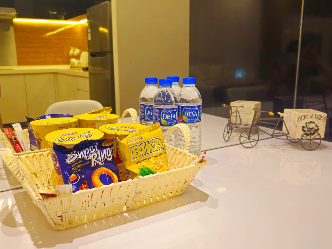 Uma cesta com lanches e água engarrafada sobre uma mesa.