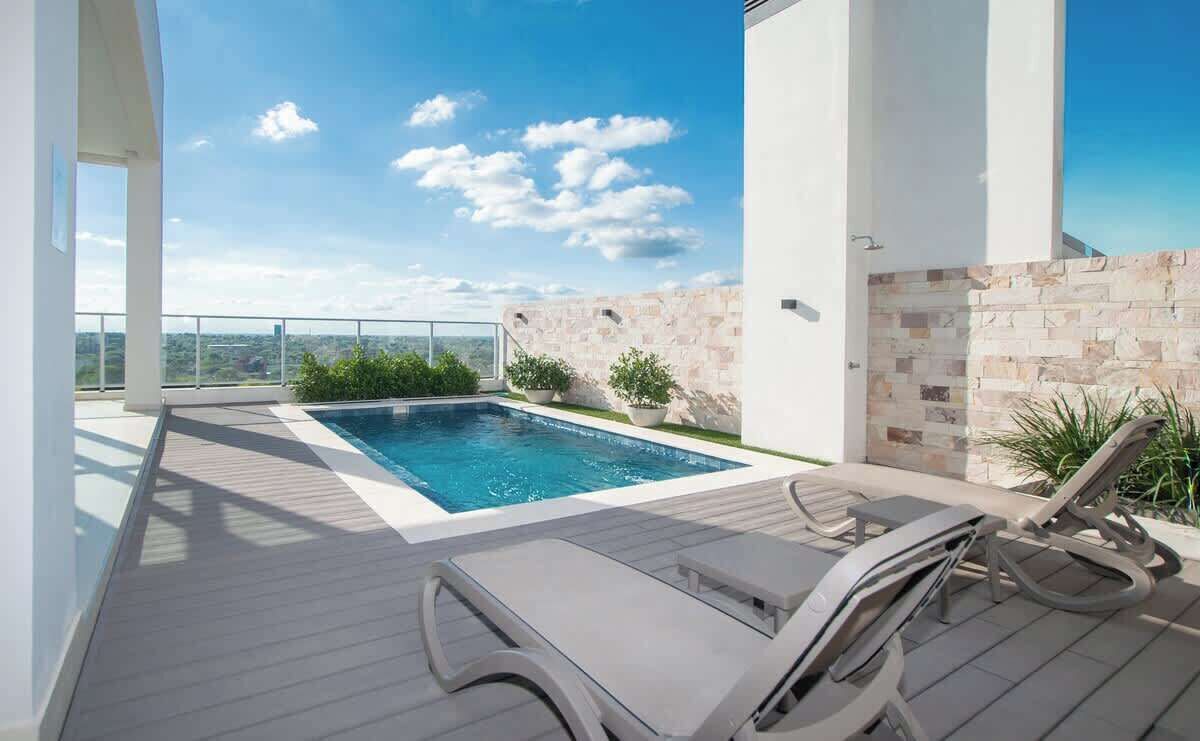 Uma piscina no terraço com espreguiçadeiras, um muro de pedra e vista para a paisagem.