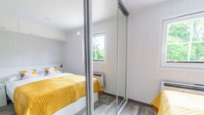 Quarto de hotel com cama, janela, espelho e guarda-roupa.
