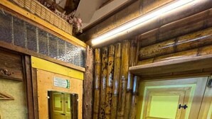 Quarto com paredes de madeira, um espelho e uma porta.
