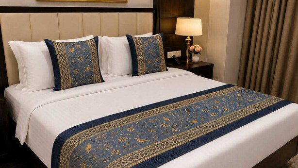 Quarto de hotel com uma cama grande, cabeceira, mesa de cabeceira com abajur e janela com cortinas.