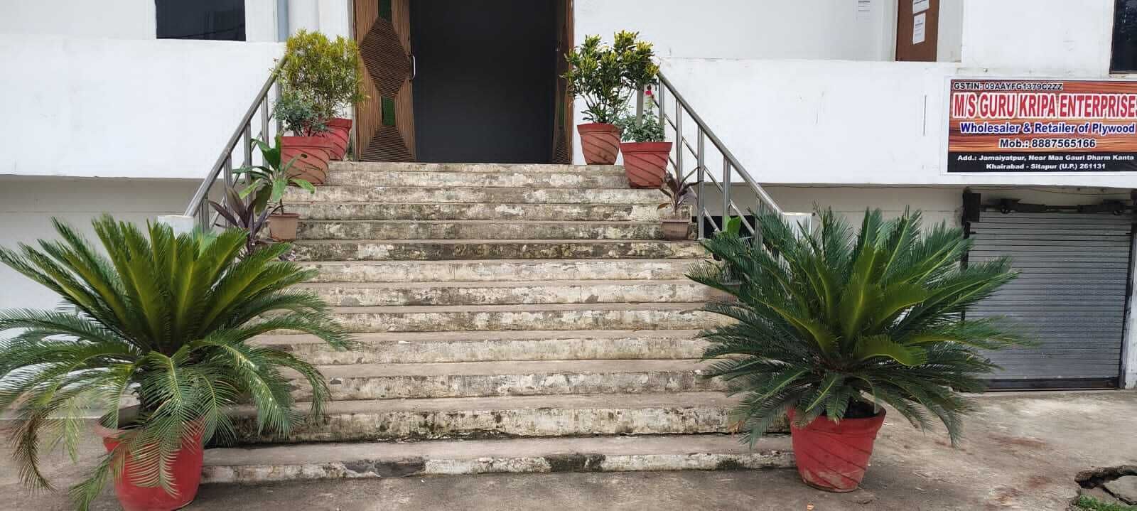 Escadaria que leva à entrada de um edifício, com plantas em vasos de ambos os lados.
