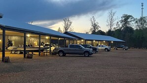 Um hotel com vários quartos, estacionamento coberto e terreno de cascalho.