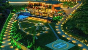 Hotel com heliponto, rodeado por um caminho bem iluminado e vegetação.