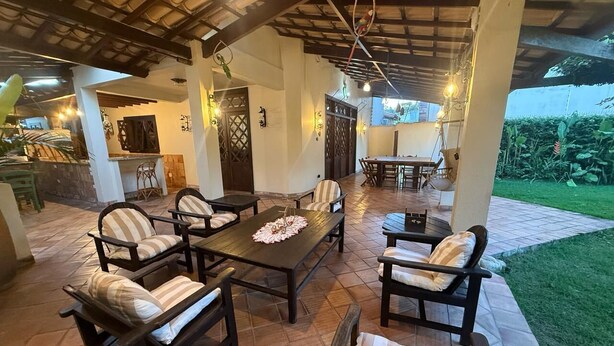 Um pátio externo com móveis de madeira, uma mesa de jantar e vista para o jardim.