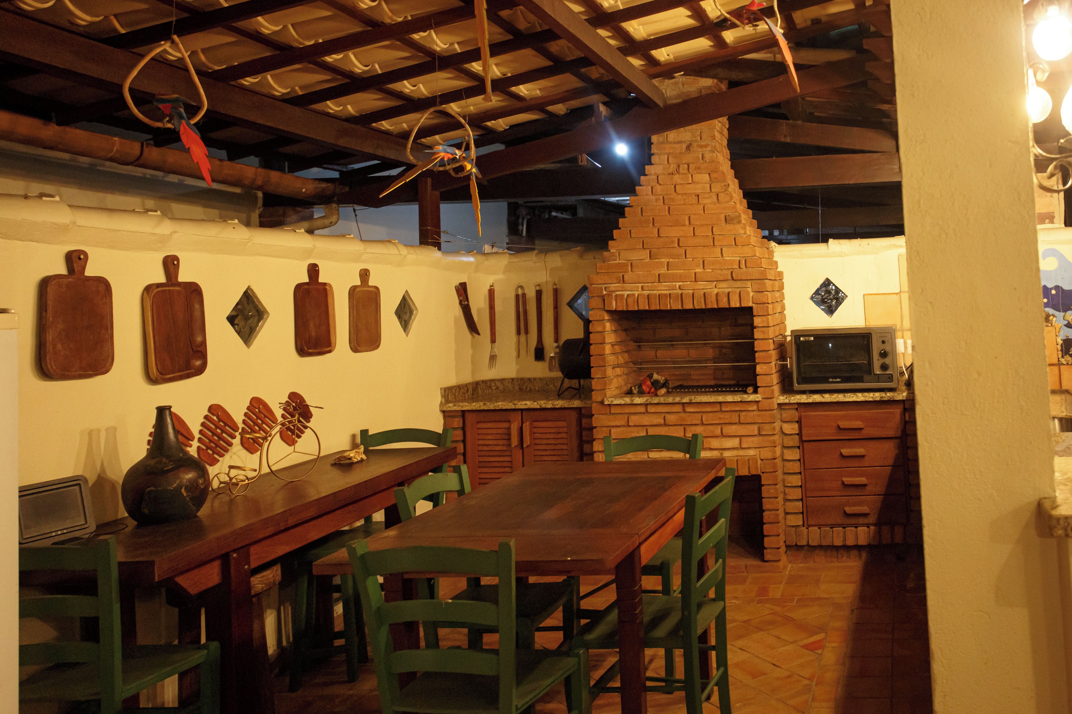 Cozinha com forno de tijolos, móveis de madeira e diversos utensílios.