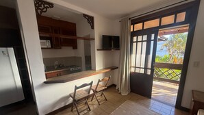 Uma cozinha com micro-ondas embutido, armários de madeira, uma TV em uma prateleira e uma porta de vidro deslizante que dá para uma varanda.