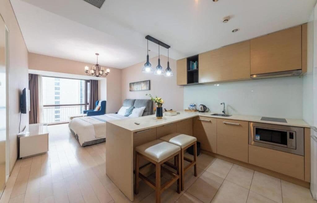 Cozinha moderna com ilha central, área de refeições com sofá e uma janela grande que oferece luz natural.