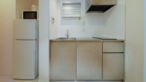 Cozinha compacta com micro-ondas integrado, pia e fogão.