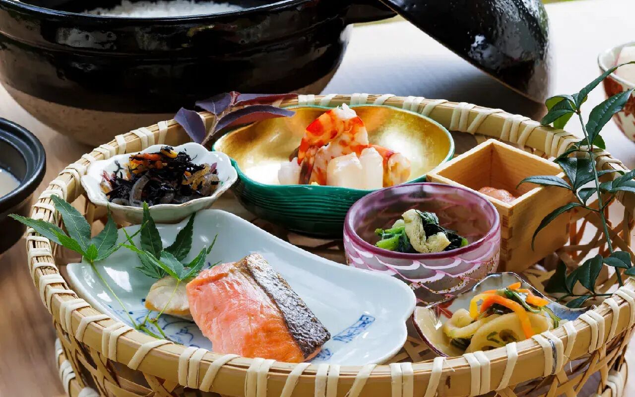 Uma refeição tradicional japonesa com diversos pratos, incluindo salmão, frutos do mar e legumes.