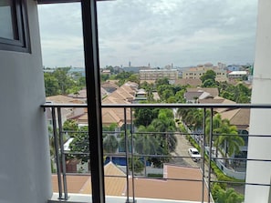 Área residencial com várias casas, céu claro e vista pela janela com guarda-corpo de varanda.