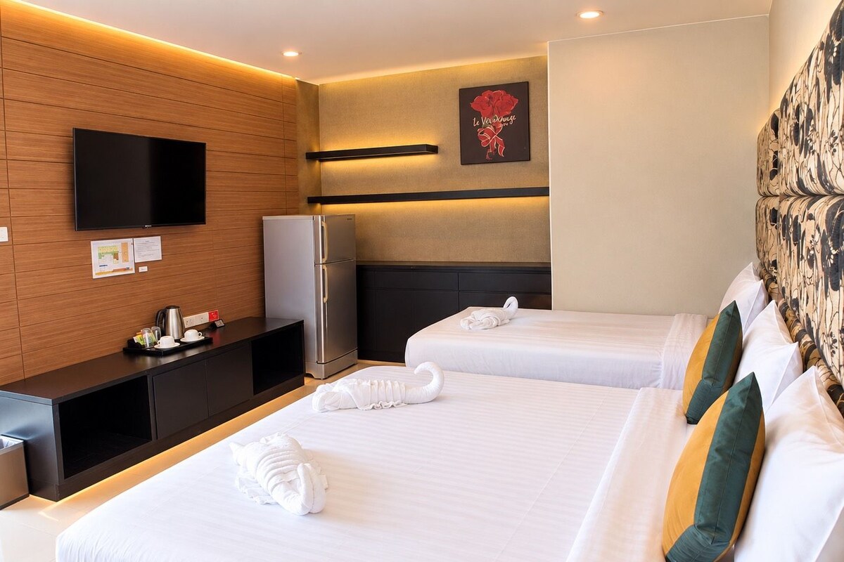 Quarto de hotel com duas camas, televisão de tela plana, geladeira, cafeteira e uma obra de arte na parede.