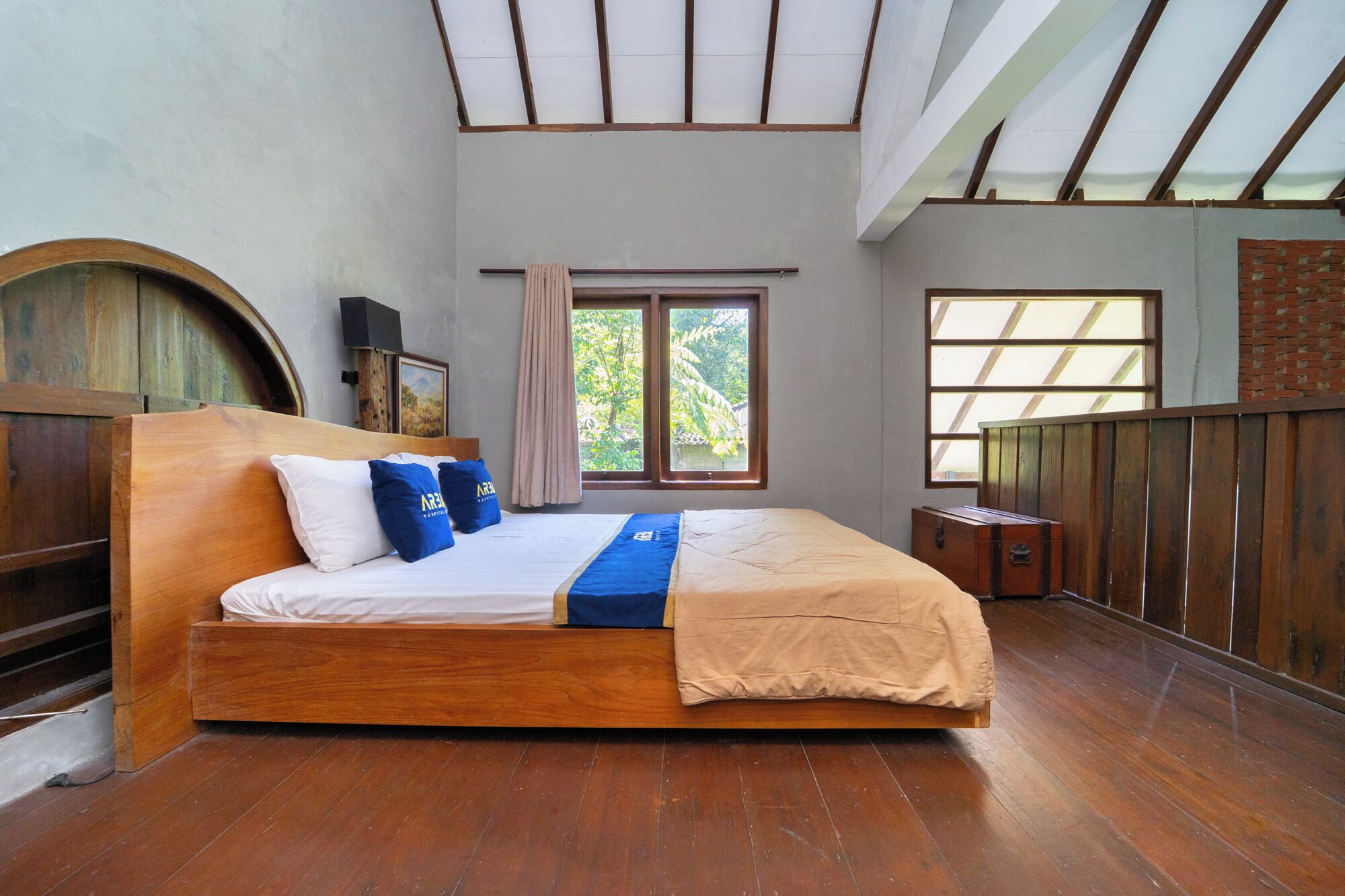 Uma cama de madeira com almofadas, uma janela com vista e cabeceira de madeira.