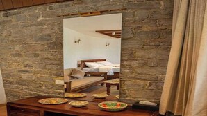 Um espelho sobre a cama e uma mesa de madeira com pratos decorativos.