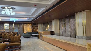 Um hall amplo com balcão de recepção, área de estar e um candelabro.