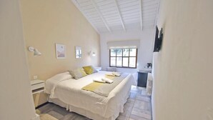 Um quarto com cama, mesas de cabeceira, janela e radiador.