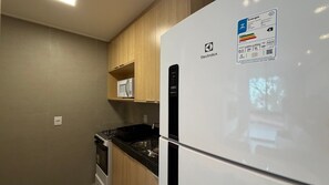 Uma cozinha com geladeira branca, micro-ondas e fogão.