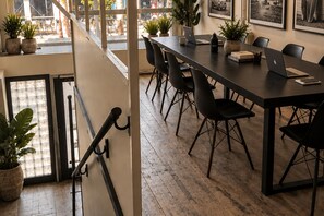 Uma sala de conferências moderna com uma mesa comprida, cadeiras pretas e plantas em vasos.