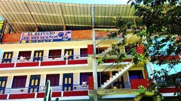 Um edifício de vários andares com varandas e uma placa que diz 'EL REFUGIO DE MIS SUEÑOS'.