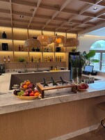 Cozinha moderna com bancada de mármore, uma fruteira e um climatizador de vinhos.