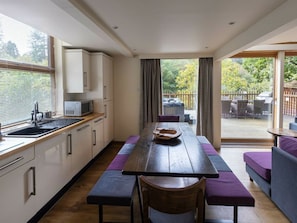 Cozinha moderna com mesa de jantar, bancos e vista para o exterior.