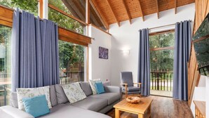 Uma sala de estar moderna com um sofá cinzento, mesa de centro de madeira e uma poltrona.
