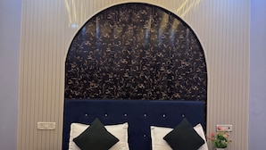 Quarto com cama, cabeceira, mesa de cabeceira e tomada na parede.