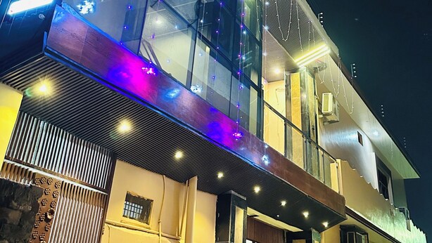 Um edifício moderno com fachada de vidro, um destaque para o letreiro 'VEDAS' e uma entrada bem iluminada.
