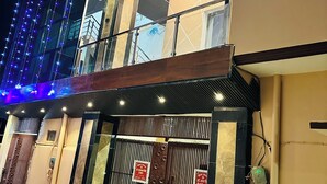 Um edifício com vários andares, fachada de vidro, entrada com portão e luzes decorativas em estilo festivo.
