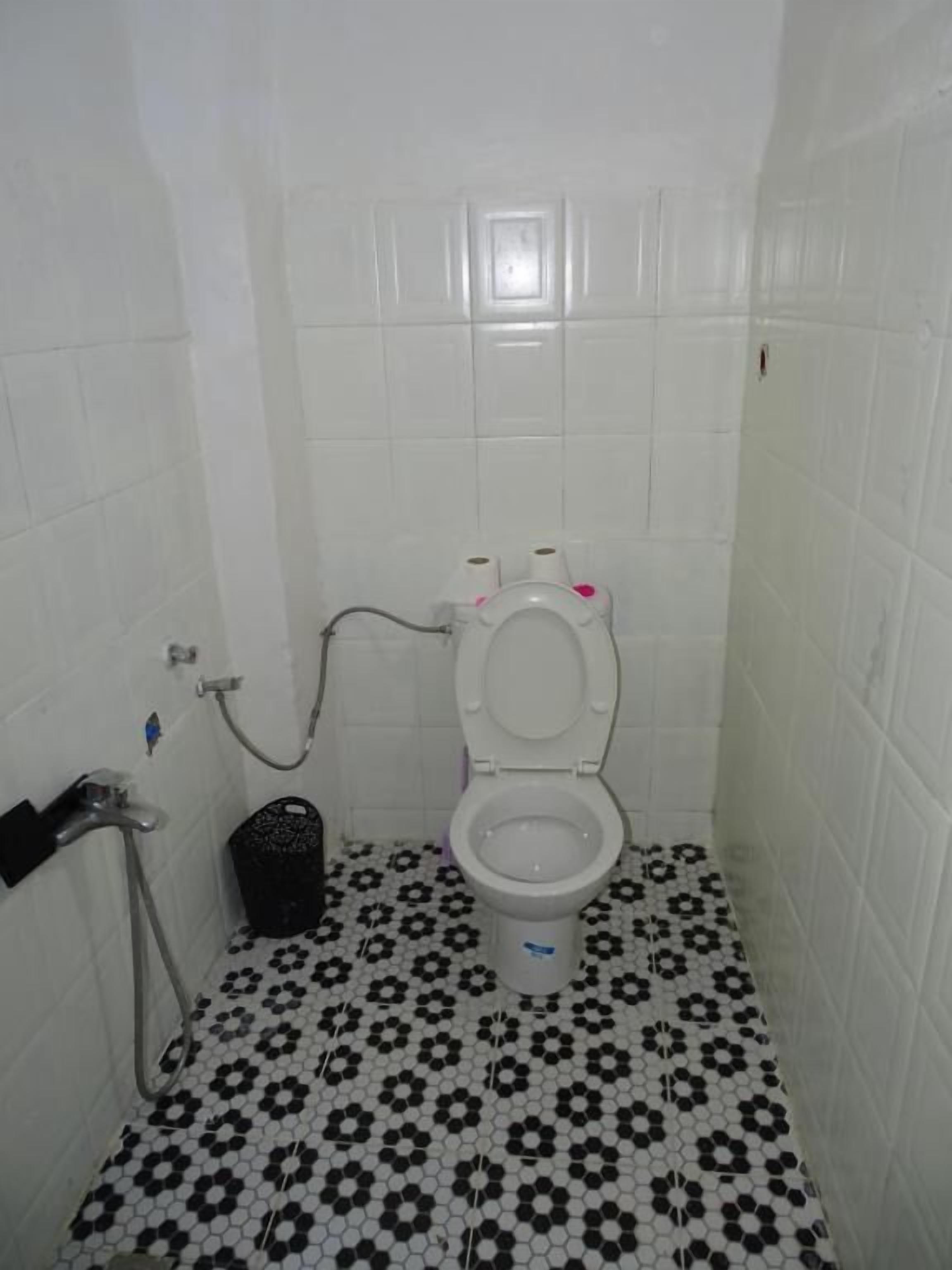 Casa de banho com sanita, secador de mãos e um contentor de lixo.