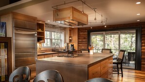 Uma cozinha moderna com uma ilha grande, eletrodomésticos de aço inoxidável e vista para o exterior.