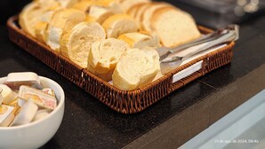 Mesa de buffet com pão fatiado e manteiga em embalagens.