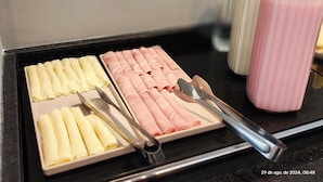 Uma bandeja com pastéis bem enrolados e um recipiente rosa para bebidas em uma bancada.