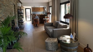 Uma sala de estar moderna com sofá, apoio para os pés e área de bar, com uma janela grande.