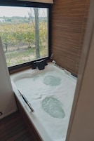 Uma casa de banho com uma janela ampla, uma banheira e um porta-toalhas.