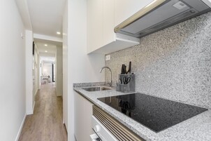 Cozinha moderna com bancada de granito, pia de aço inoxidável e coifa.