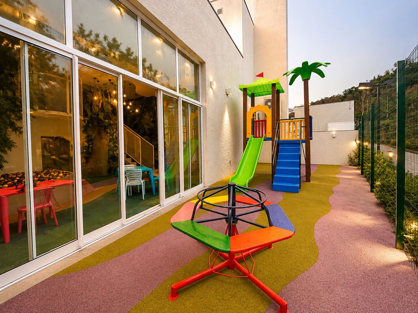 Espaço infantil com escorrega, estrutura de escalada e cadeira giratória.