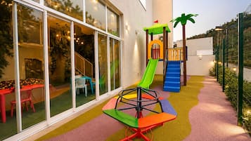 Espaço infantil com escorrega, estrutura de escalada e cadeira giratória.
