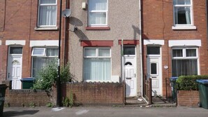 Um edifício residencial de dois andares com fachada de tijolo, janelas emolduradas em branco e uma antena parabólica visível.