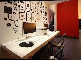 Um espaço de trabalho moderno com dois computadores, um teclado, um rato e uma impressora sobre uma mesa comprida.