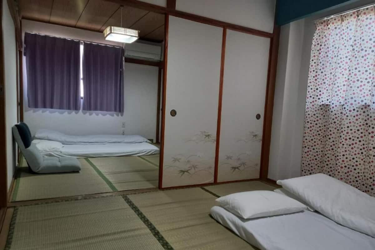 Um quarto em estilo tradicional japonês, com piso de tatame, futon e portas de papel shoji.