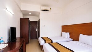 Quarto de hotel com duas camas, uma escrivaninha, uma televisão e um aparelho de ar condicionado.